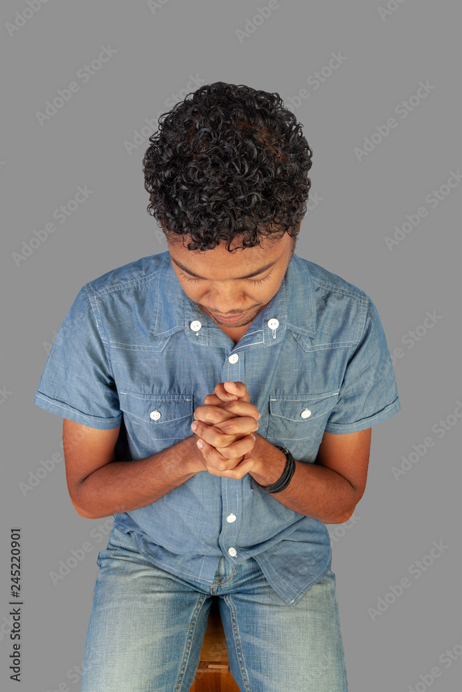 Young Indo-Mauritian or Creole Pastor in training sitting with hands in ...