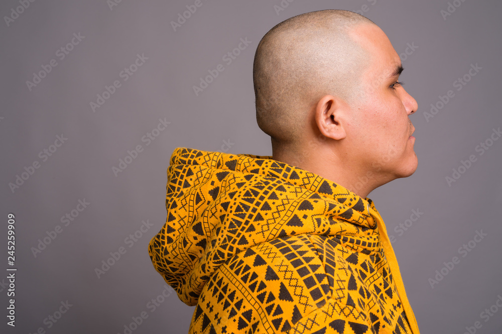 Young bald Asian man against gray background Stock Photo | Adobe Stock