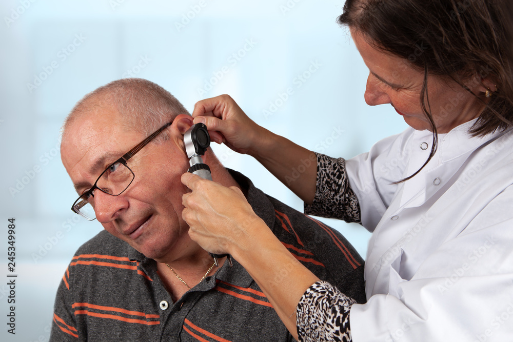 doctor examines the inner of the ears of her patiënt with an otoscope ...