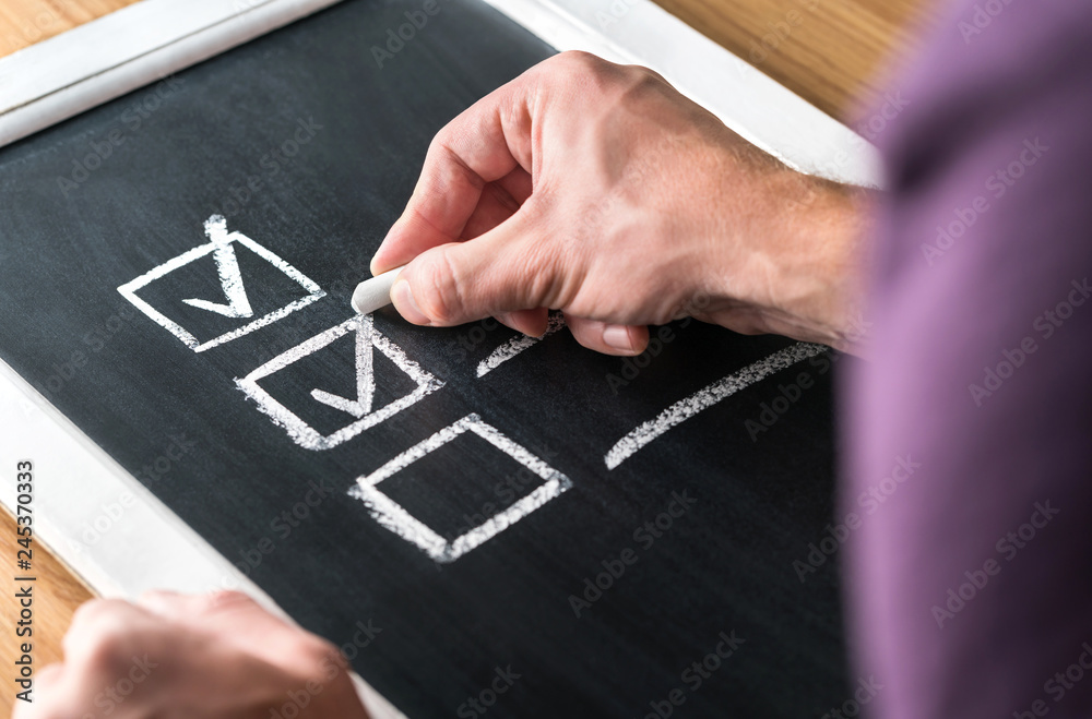 Man writing checkmark to checklist on blackboard. Document of finished ...