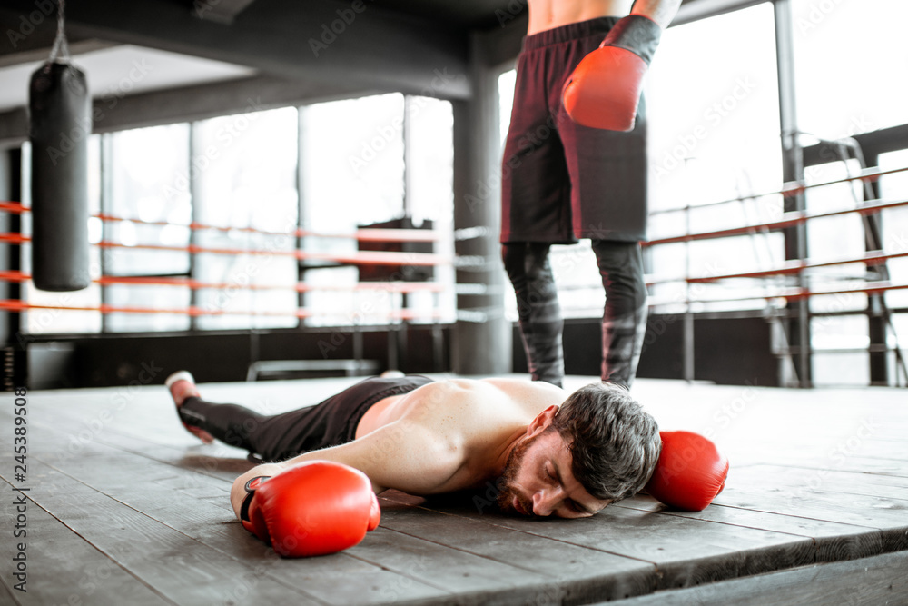 Beaten boxer lying on the floor during a boxing battle, having a ...