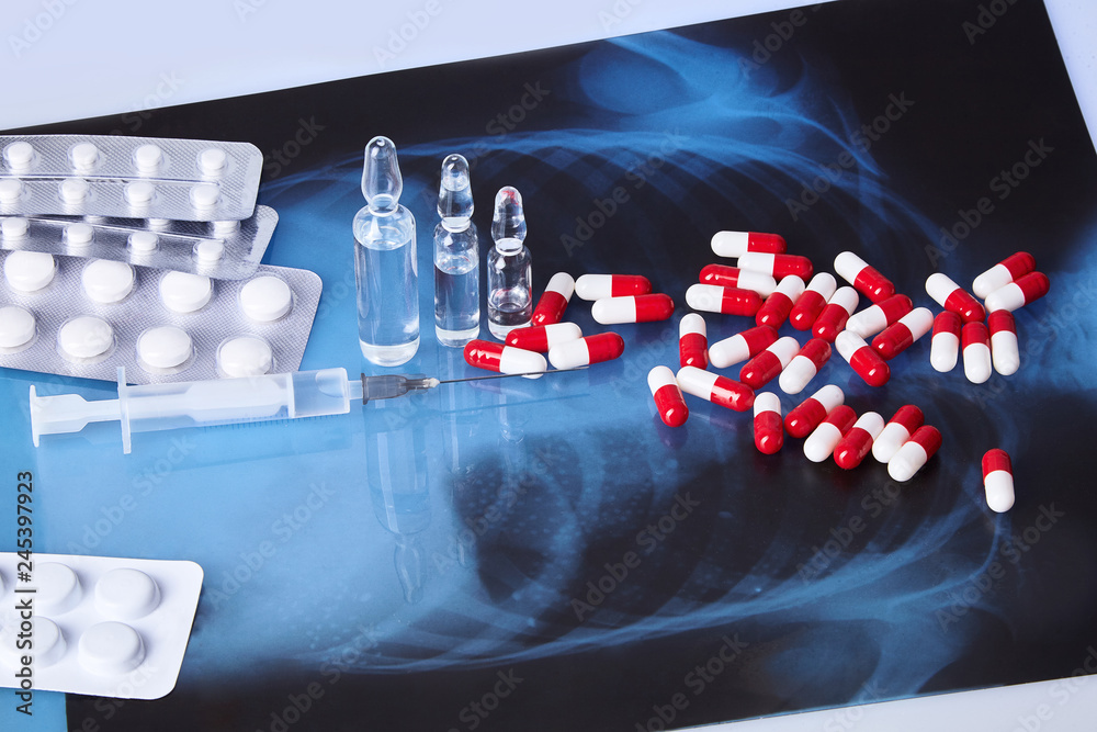Scattered capsules, tablets, ampules and syringe on the table with ...
