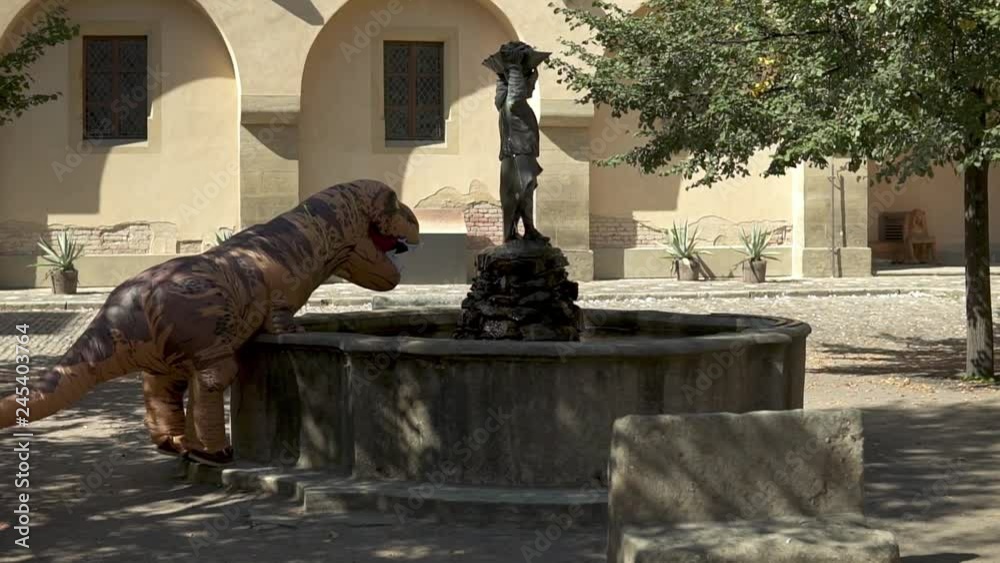 inflatable Tyrannosaurus Rex drinking water from a medieval well with a ...