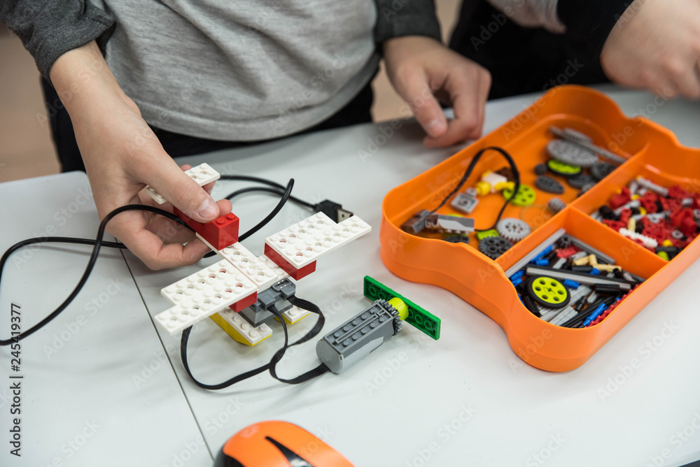Group of kids building robot constructor from the plastics details ...