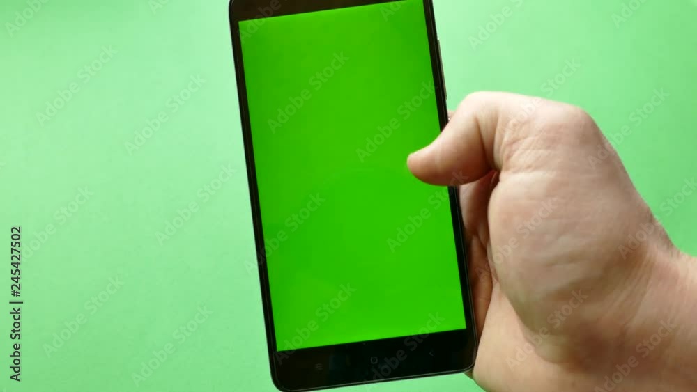 The smartphone is held in their hands and use it. Green screen in the ...
