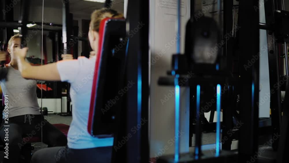 Blonde girl develops the muscles of the chest exercises on the power ...