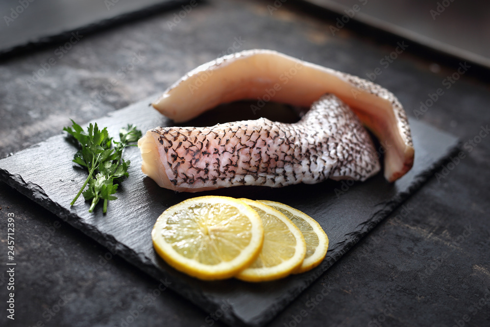 Grenadier na kamiennym talerzu. Surowa ryba na czarnym kamieniu i ...