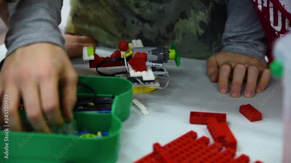 Group of kids building robot constructor from the plastics details ...