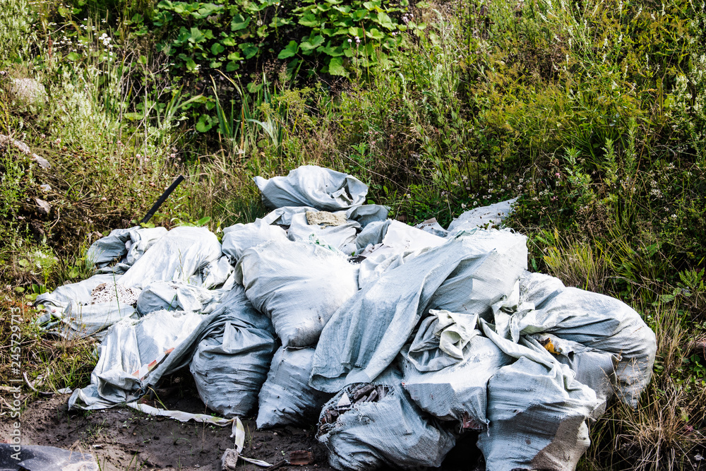 Trash on the grass. Construction waste. Rubbish in bags. Damage to the ...