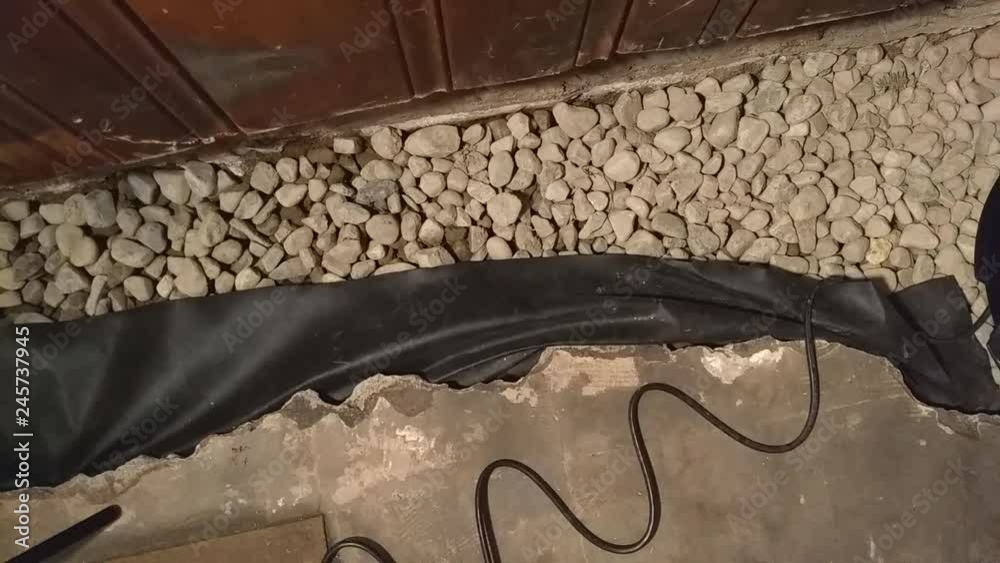 An open french drain prior to being covered with concrete. The camera ...