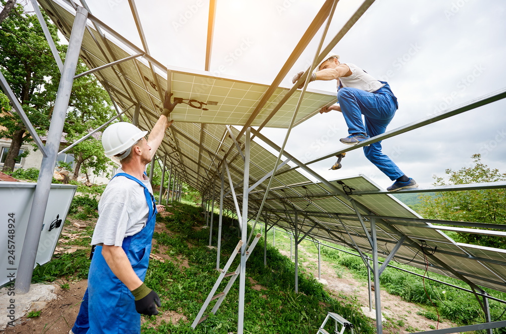 Installing of solar photo voltaic panel system. Three technicians ...