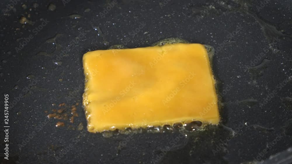 Sliced cheddar melting into a cheese crisp on the stove Stock Video ...