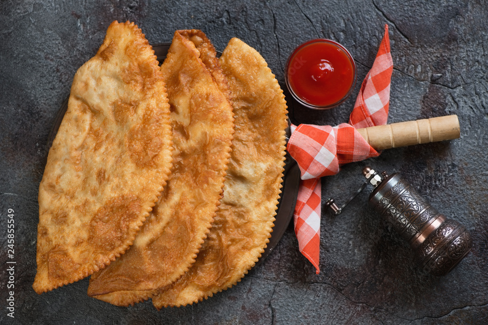 Above view of freshly cooked chebureki or chiburekki pies on a grey ...