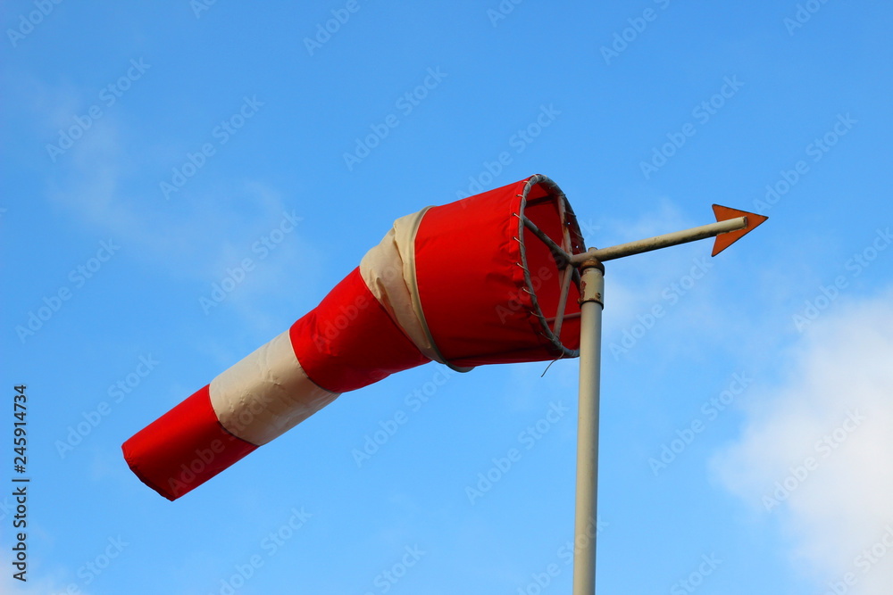 Windsock with a weather vane in front of a blue sky with white clouds ...