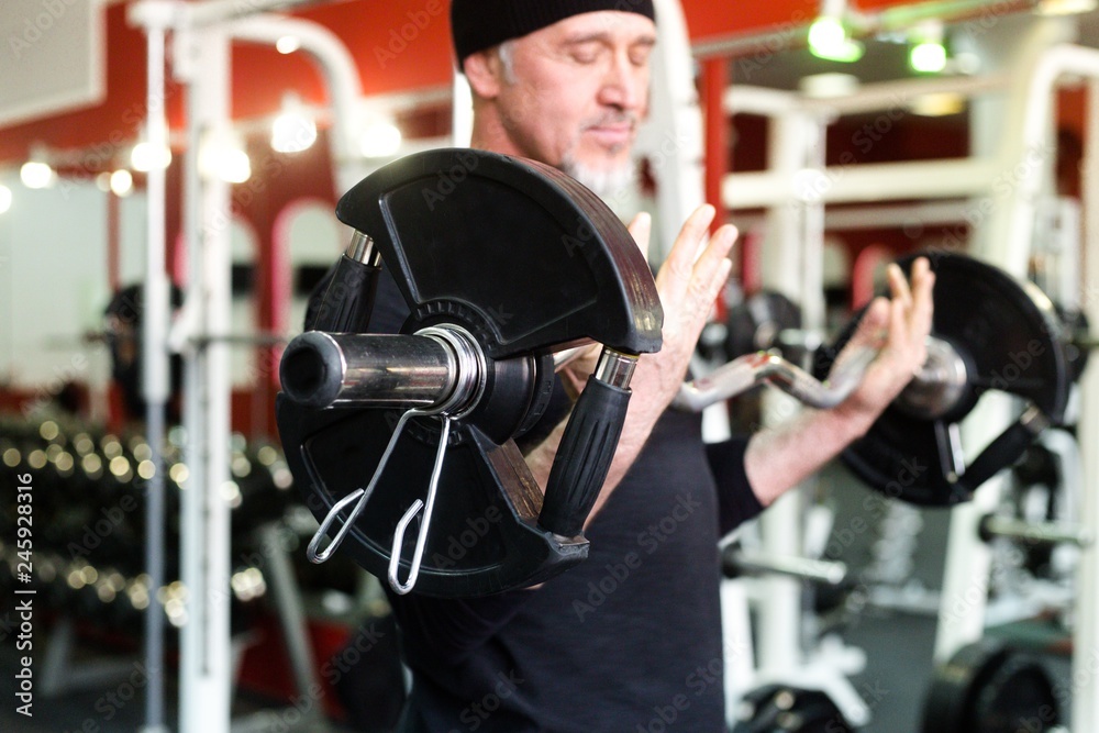 Adult male athlete with a gray beard practices lifting heavy barbell ...