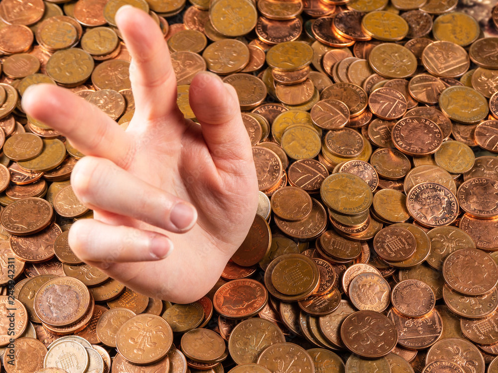The hand which is sticking out of heap of coins Stock Photo | Adobe Stock