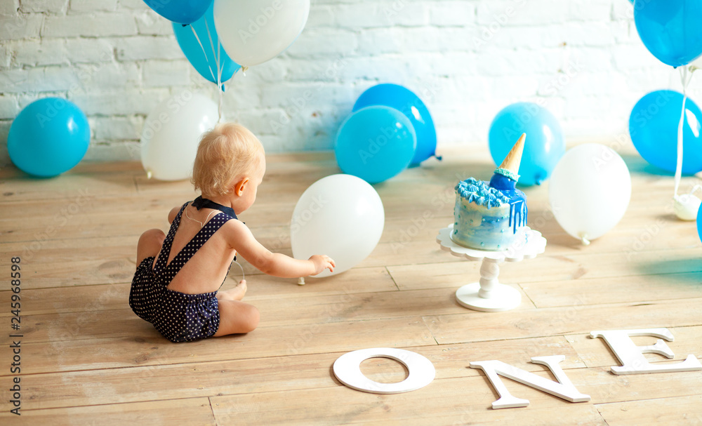 One year old boy is celebrating his first birthday among a balloons and ...