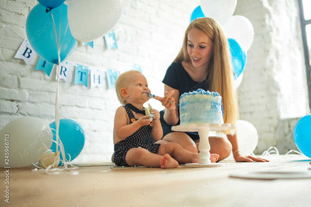 Mother is celebrating first birthday of her son and feeding his by cake ...