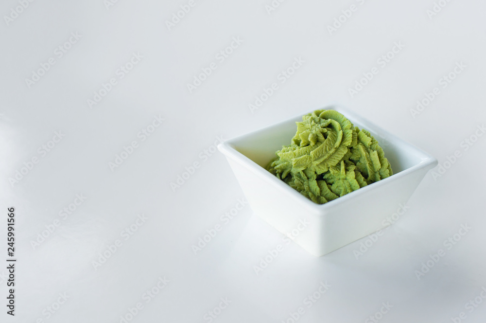 Wasabi portion for sushi and rolls in a square bowl isolated on a white ...
