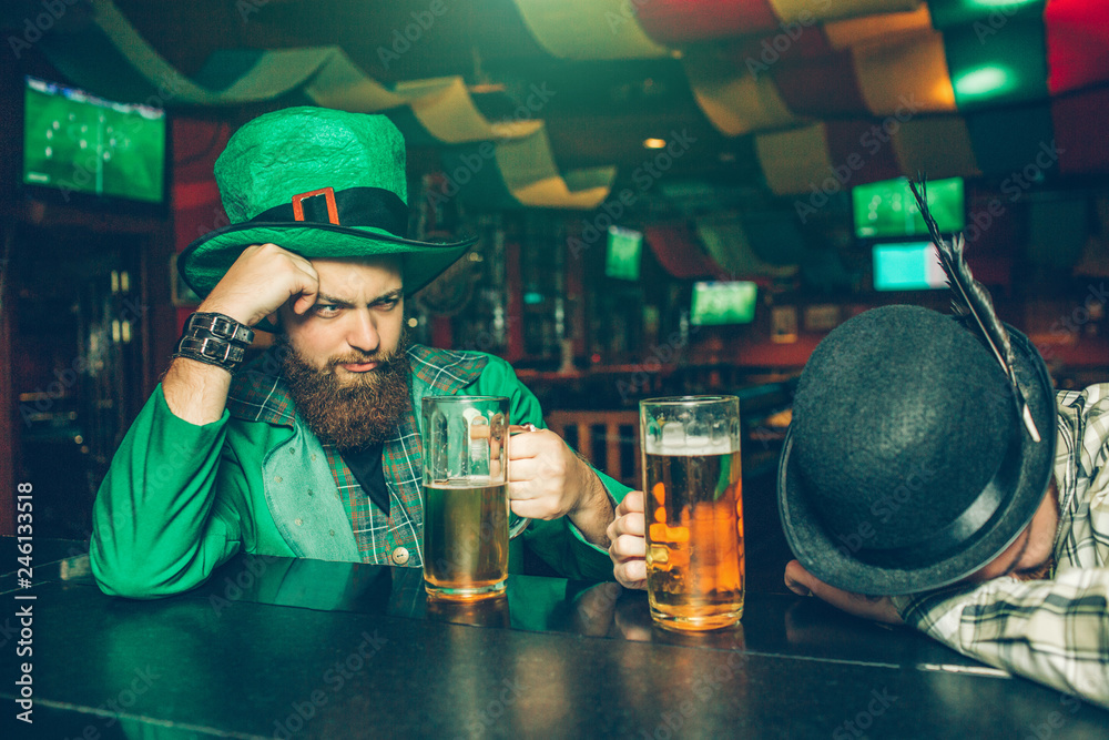 Drunk young man in green suit sit at bar counter in pub with friend ...