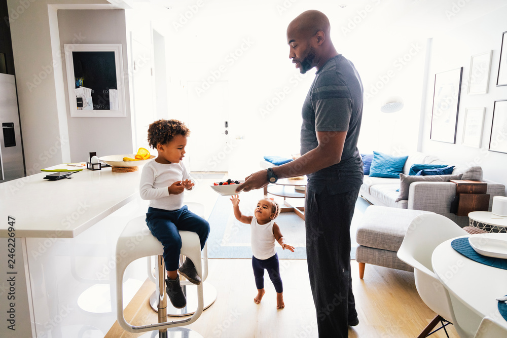 Side view of father offering berry fruits to children at home Stock ...