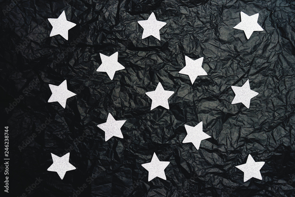 Diy background of silver stars over a crumpled black paper background ...