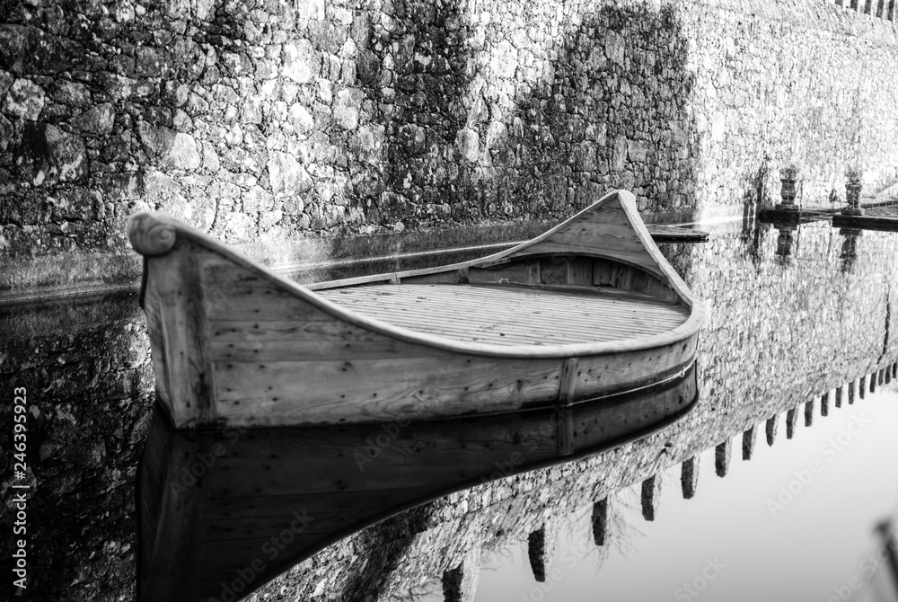 Barca de madera en estanque con muro de piedra y reflejo en el agua en ...