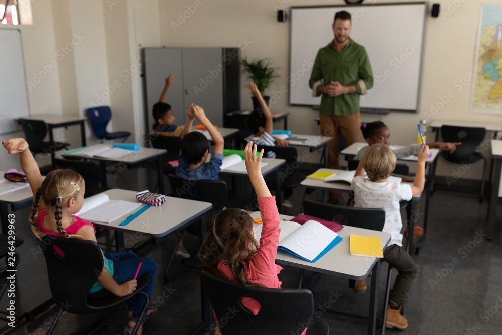School kids raising hand in classroom of elementary school Stock Photo ...