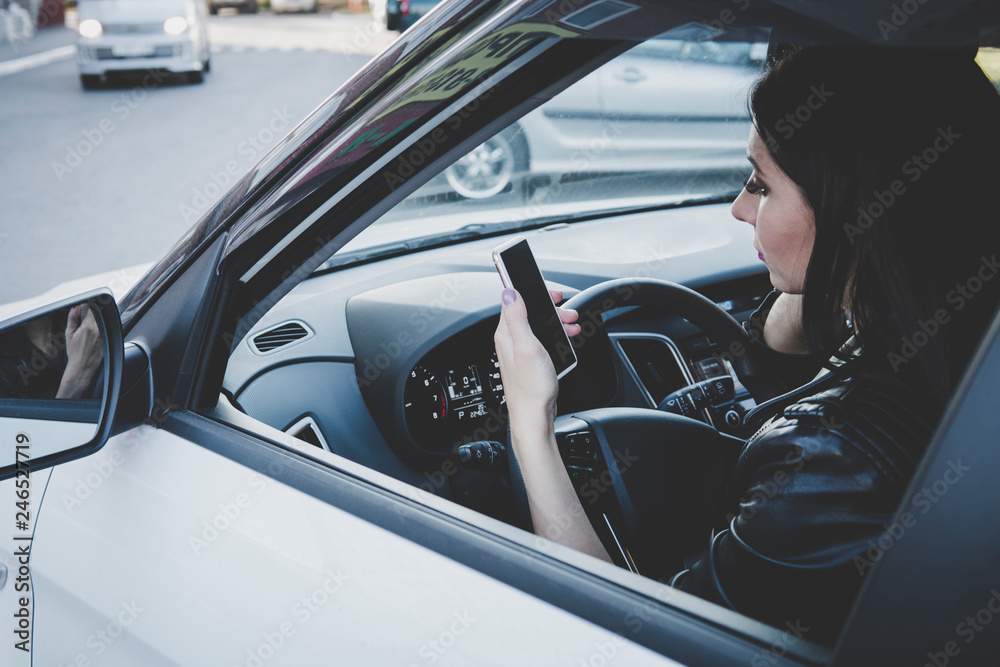 Woman using navigation app on smartphone while driving a car. Side view ...