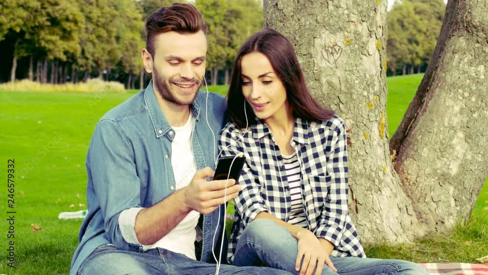 Happy couple lying under a tree and listening to music. Stock Video ...