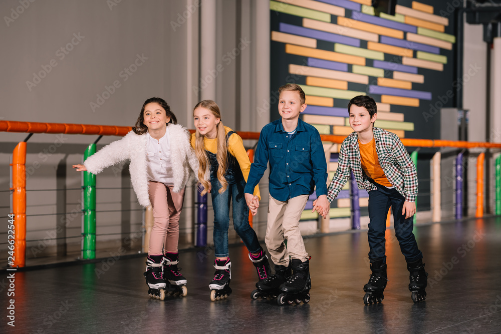 Four smiling kids holding hands while skating together Stock Photo ...