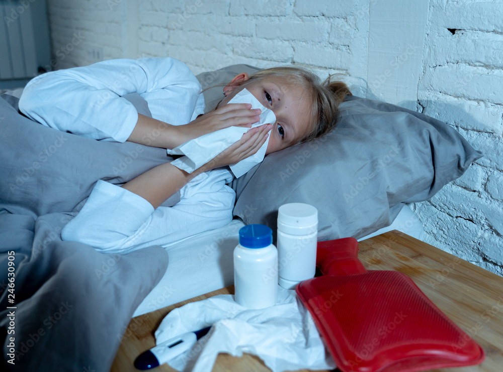 Little girl lying sick in bed blowing her nose feeling sick with high ...