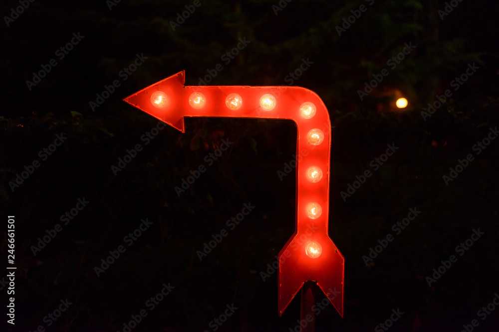 Red burning arrow pointer. Night time Walk through the park. Trees are ...