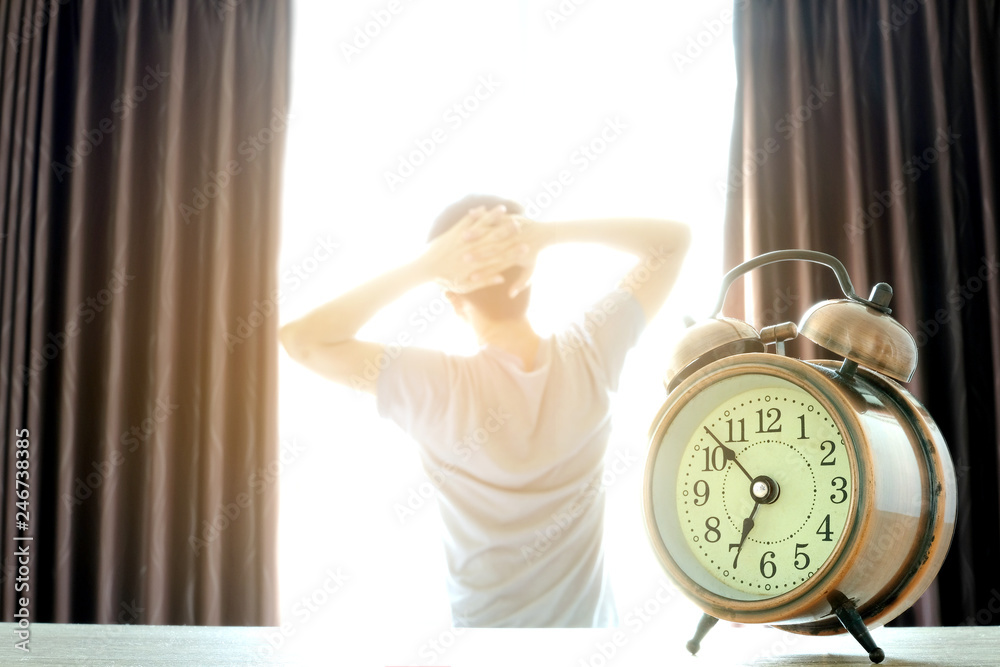 Morning of a new day, alarm clock wake up man sitting in the room. A ...