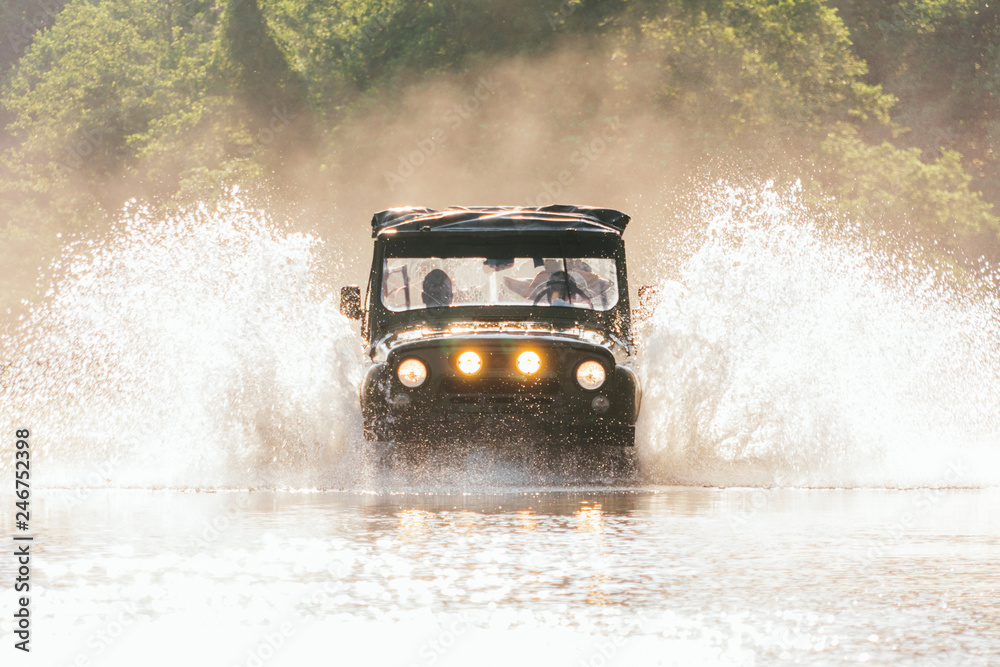 Old classic 4x4 car crossing water with beautiful splashes in a warm ...