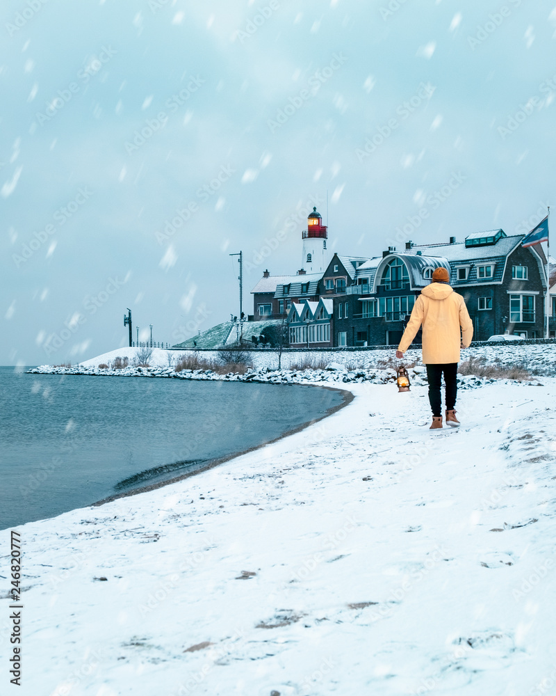 young men in yellow rain jacket on the beach with snowy weather, snwo ...