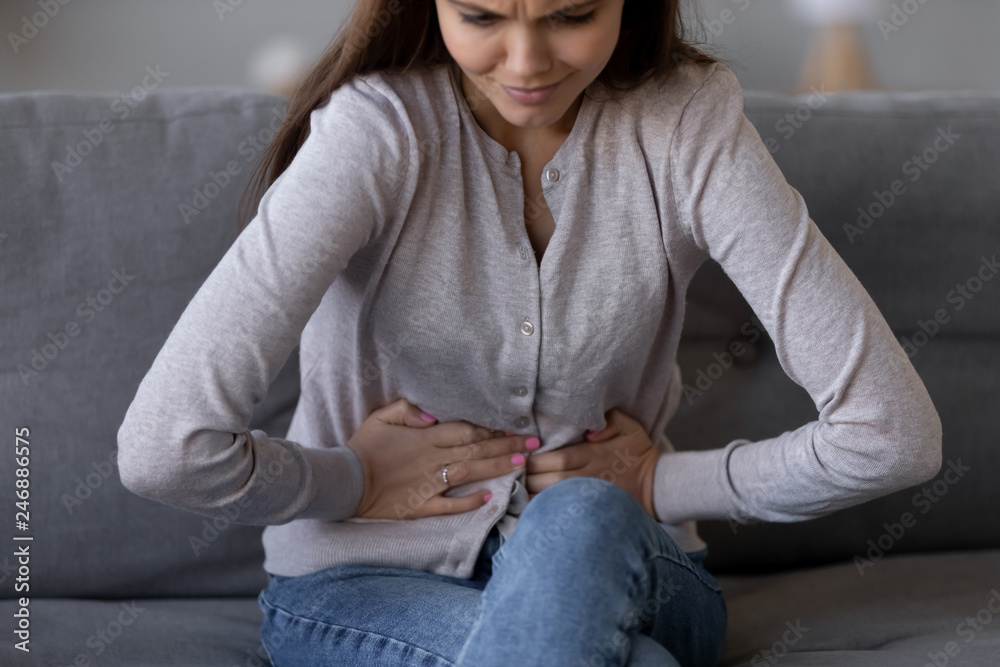 Sick young woman in pain holding belly stomach feeling hurt abdomen ...