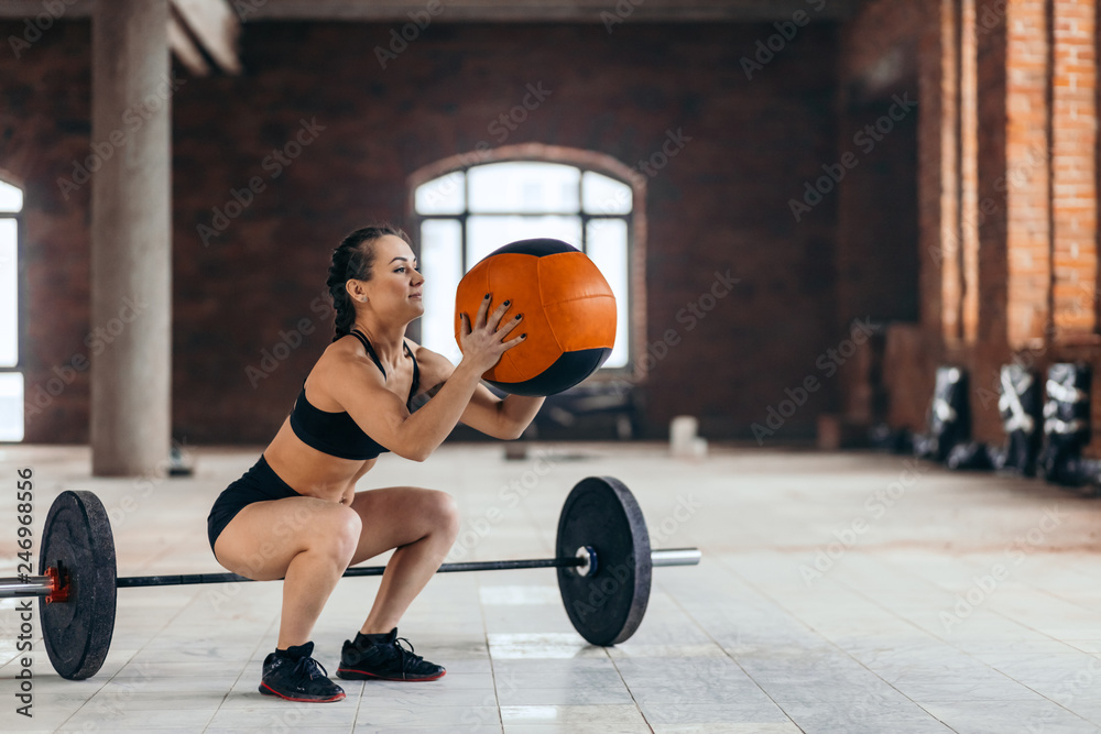 well-built motivated girl doing squat exercises with fitness ball ...