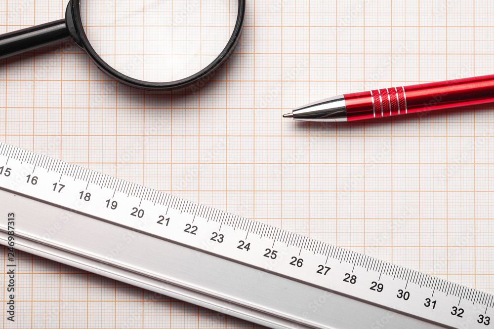 Top view engineering background. Silver ruler, red pen and magnifying ...