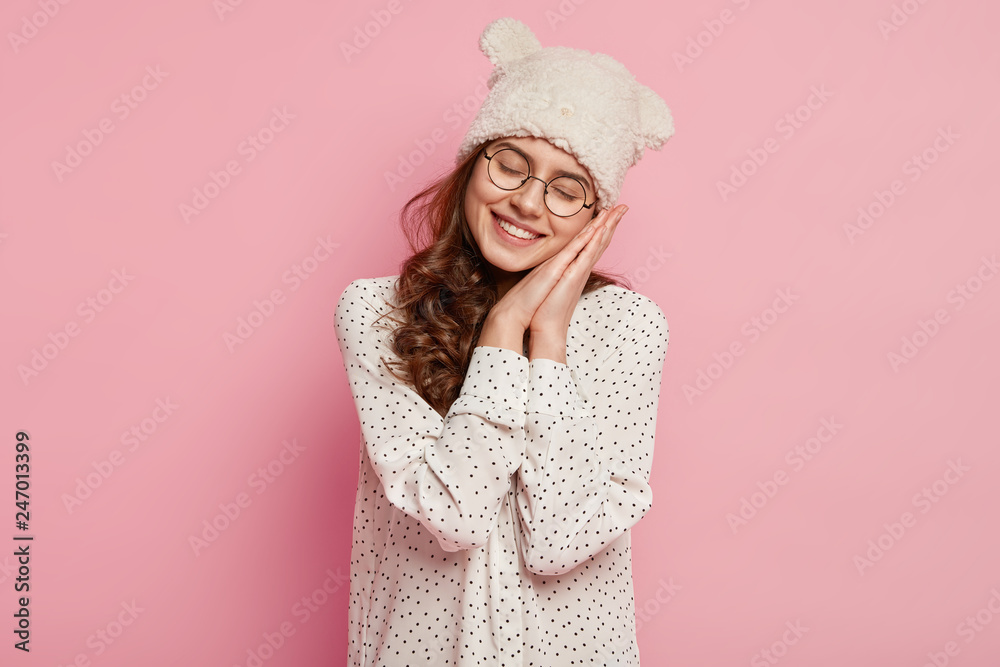Happy young woman pretends sleeping, leans on hands, has tender smile ...