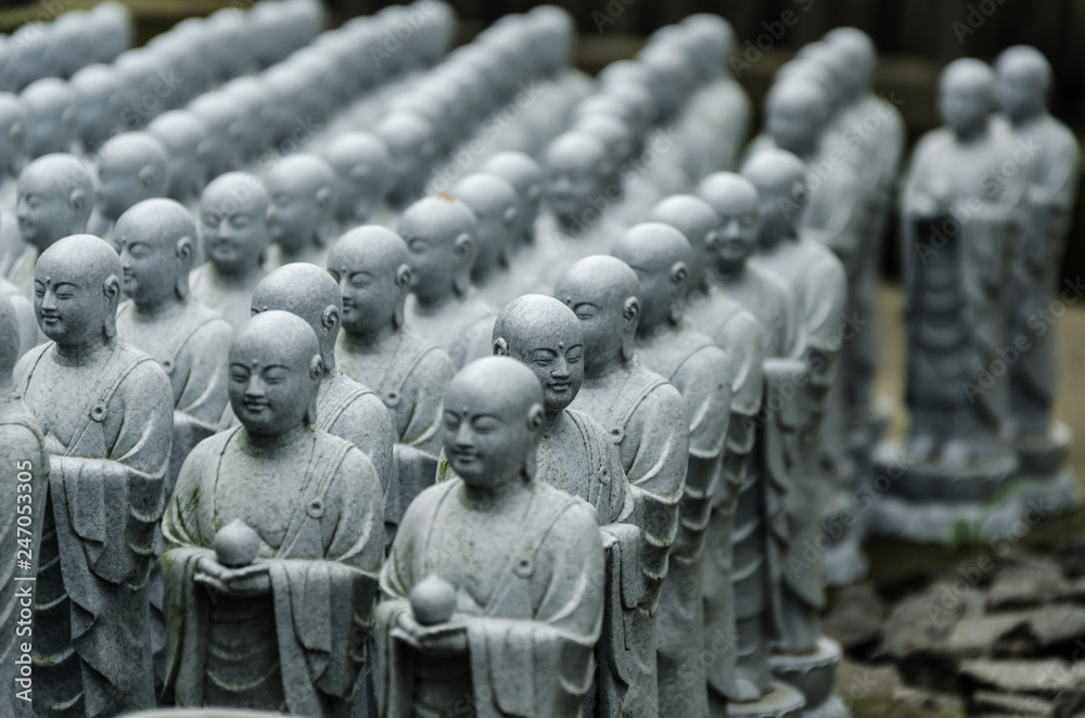 Row of stone statue of monks zen meditating and praying in the asian ...
