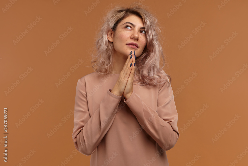 Attractive female hipster pressing hands together and looking up with ...