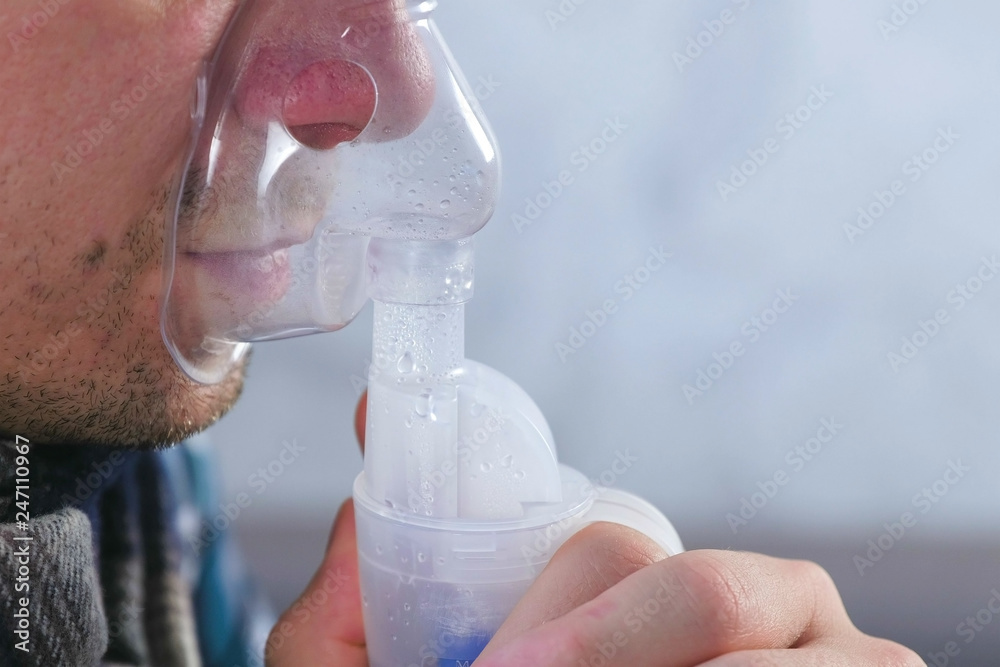 Use nebulizer and inhaler for the treatment. Sick man inhaling through ...