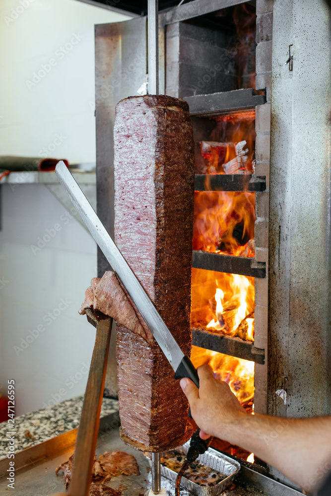 Turkish Doner Kebab, Shawarma or Gyros. Chef cutting with doner knife ...