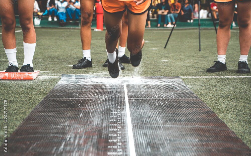 Students boy taking long jump on rubber board pid or sand pid during a ...