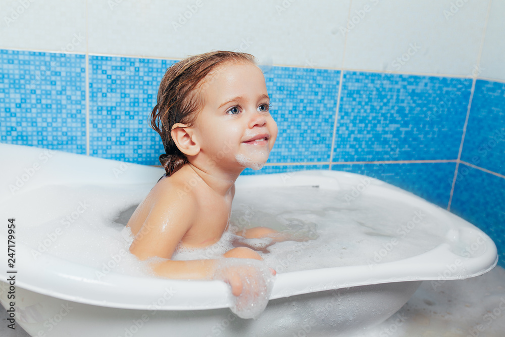 Fun cheerful happy toddler baby taking a bath playing with foam bubbles ...