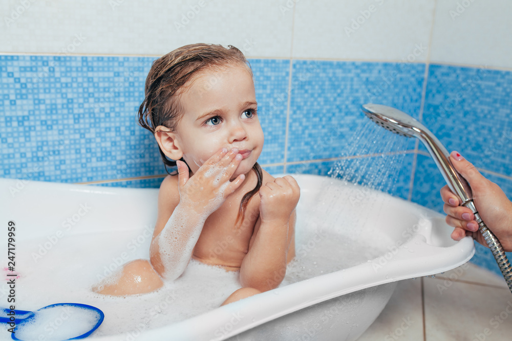 Beautiful little girl taking a bath at home. A cute baby is sitting in ...