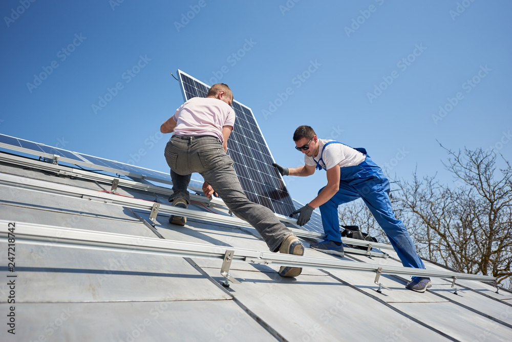 Male workers installing stand-alone solar photovoltaic panel system ...