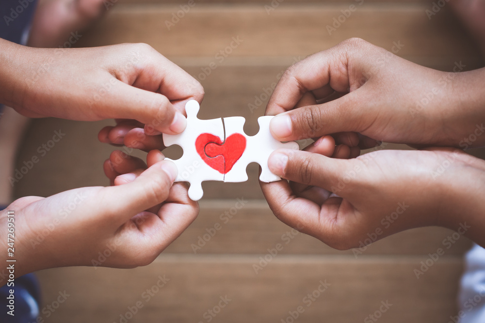 Two kid hands connecting couple jigsaw puzzle piece with drawn red ...