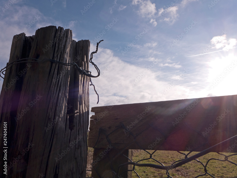 Ein Zaunpfahl aus verwittertem Holz umwickelt mit Draht an einem Gatter ...